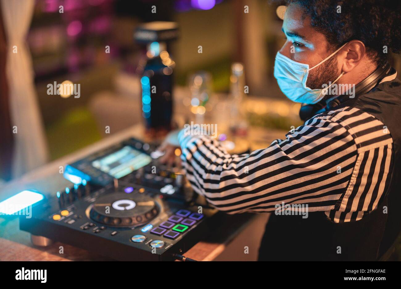 African dj playing music at cocktail bar outdoor while wearing face ...