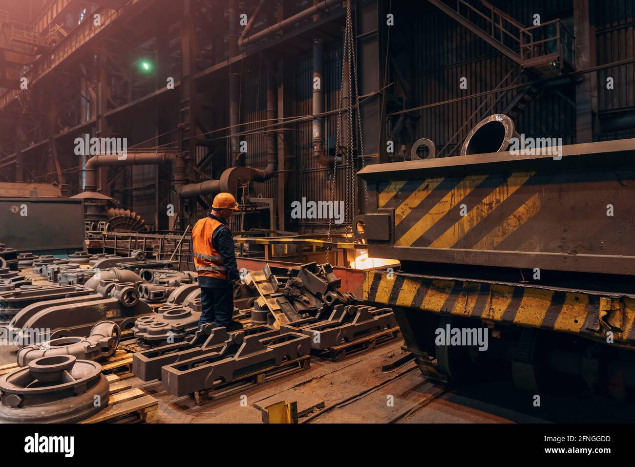 Foundry worker in workshop with cast finished metal products smelted at ...
