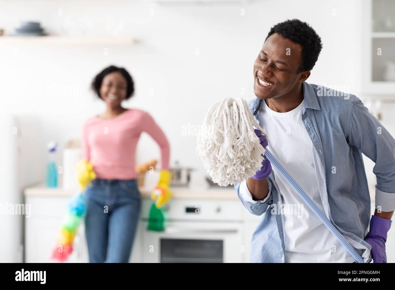 Joyful black guy using mop as microphone, singing while cleaning Stock ...