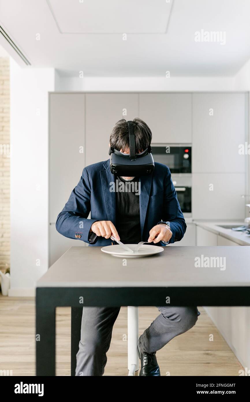 Stylish adult male pretending to eat in a modern kitchen experiencing ...