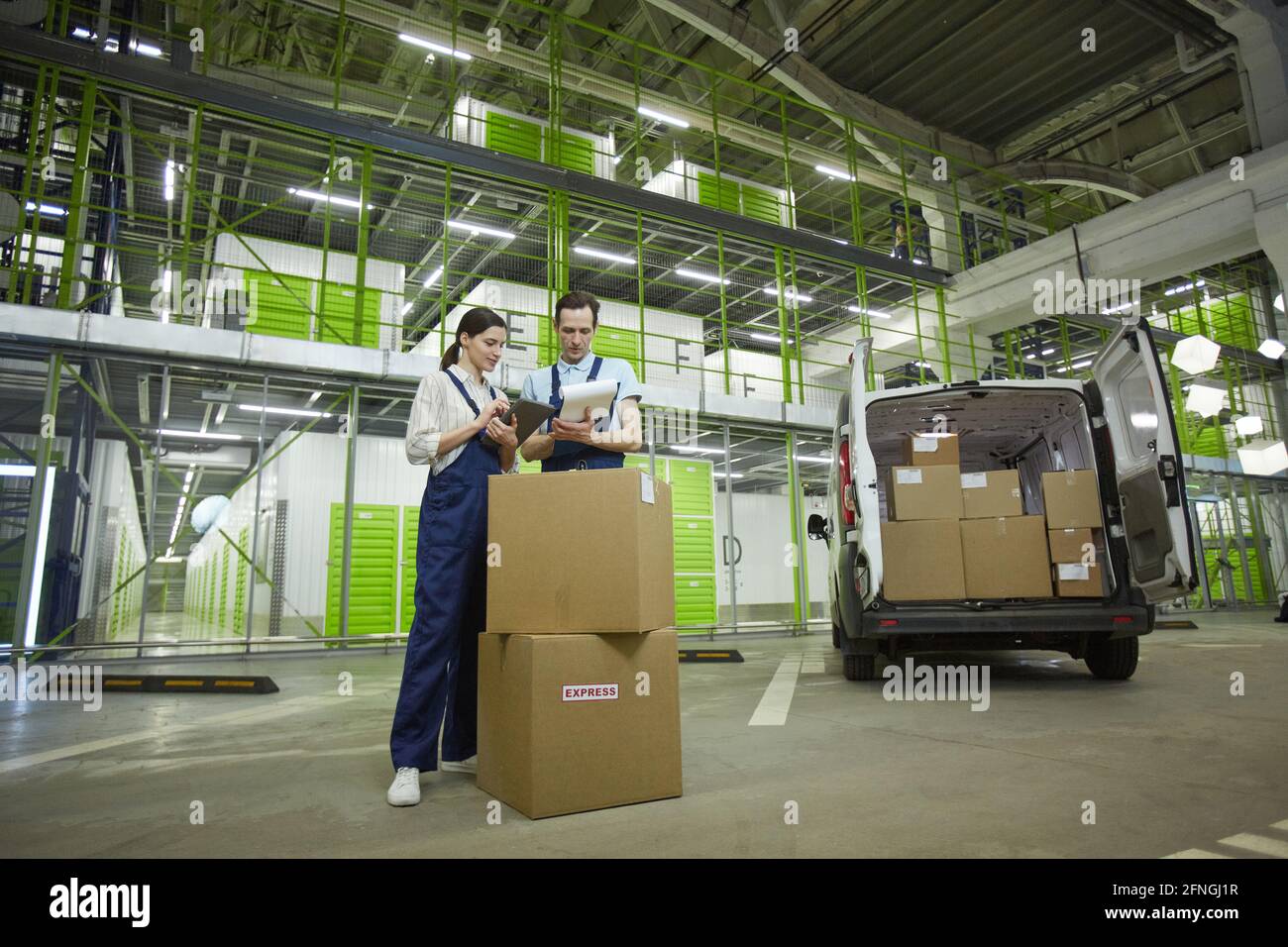 Two people packing parcels in boxes while working in delivery service ...