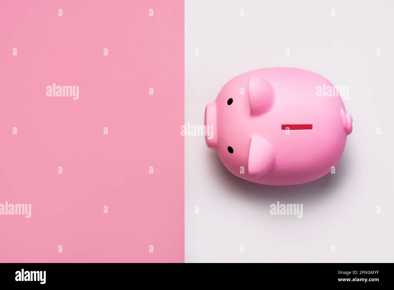 top view of pink piggy money bank with copy space on a pink and white ...