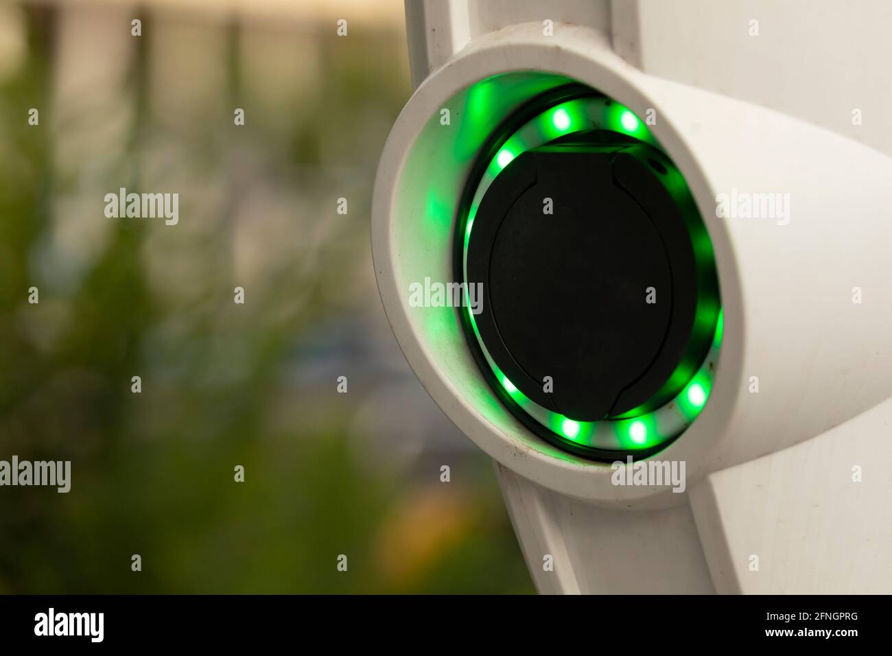 A battery charging point for electric cars, illuminated with green LEDs ...