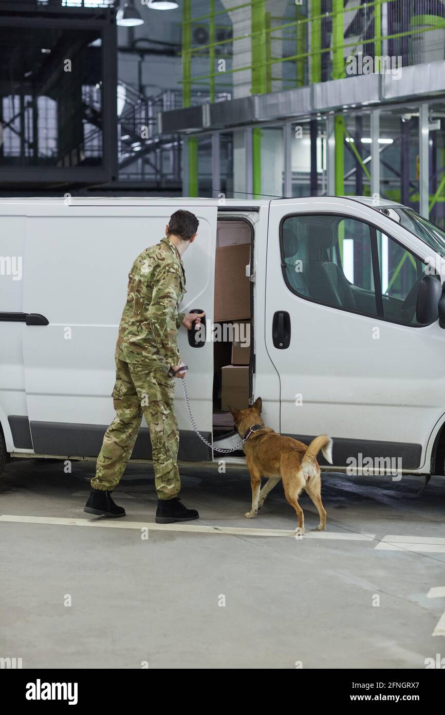 Rear view of military man with dog checking the cargo in the lorry ...