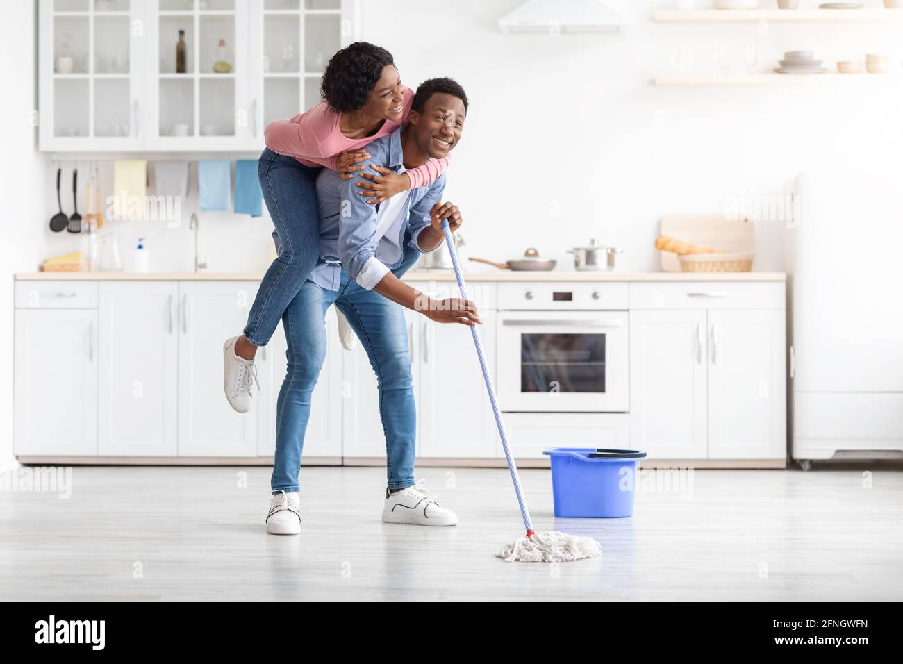 Cute black couple having fun while mopping kitchen Stock Photo - Alamy