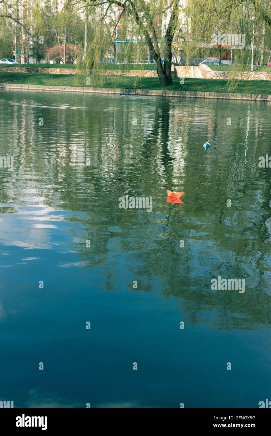 Red and white paper boats float on the water Stock Photo - Alamy