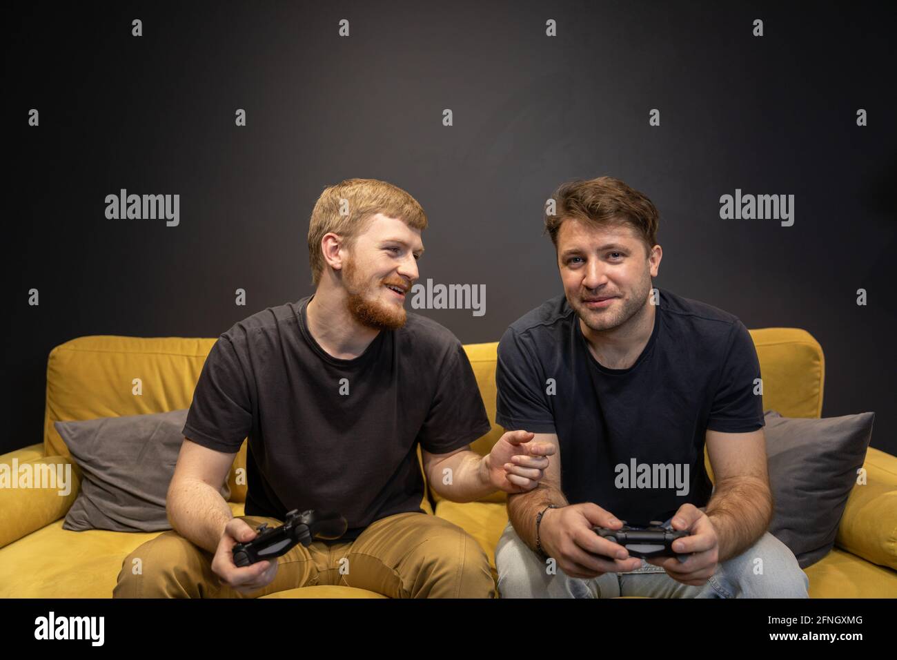 two cheerful handsome guys play passionately video game holding console ...