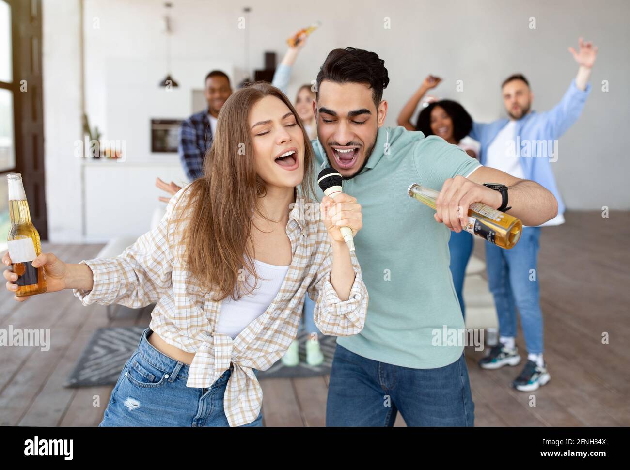 Young multiracial couple singing song together into microphone ...