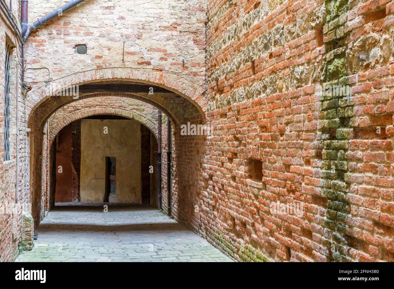 Old-fashioned alley with brick walls in an old village Stock Photo - Alamy