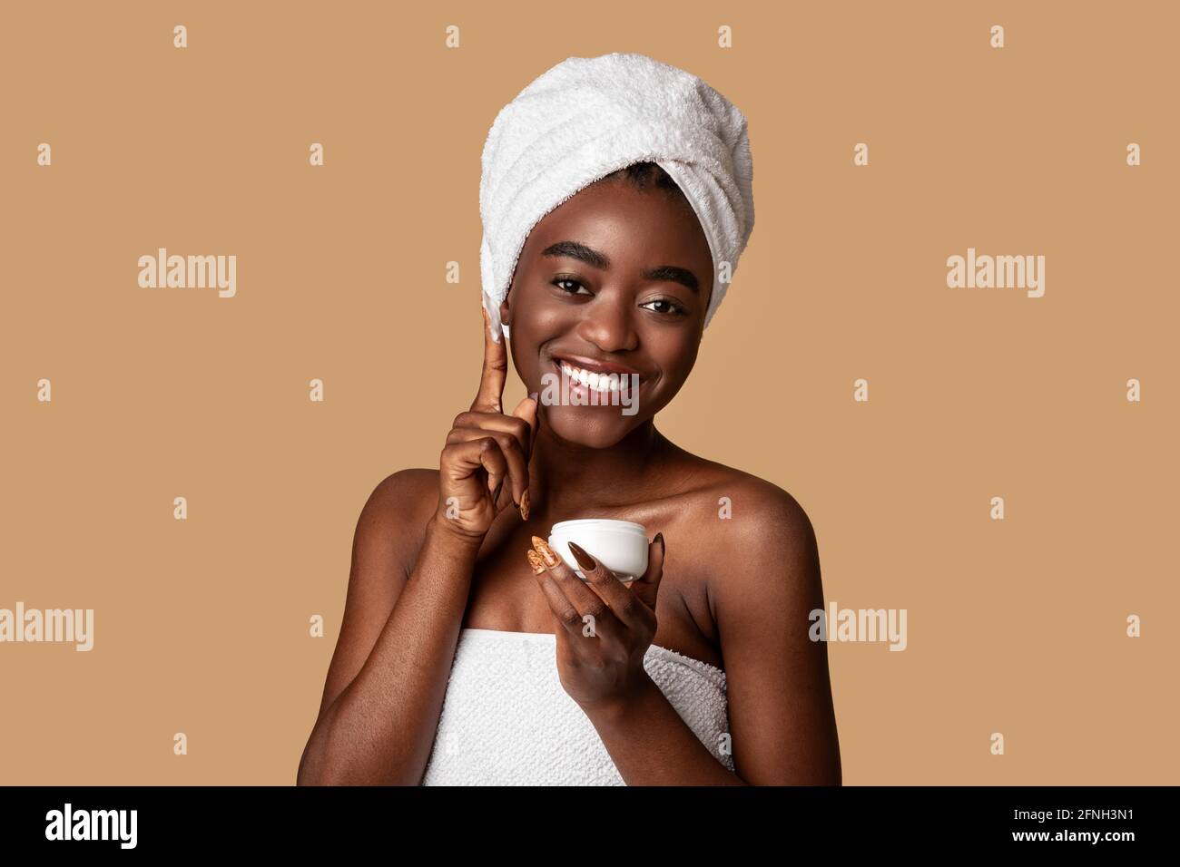 Beautiful young african american woman applying face cream from jar ...
