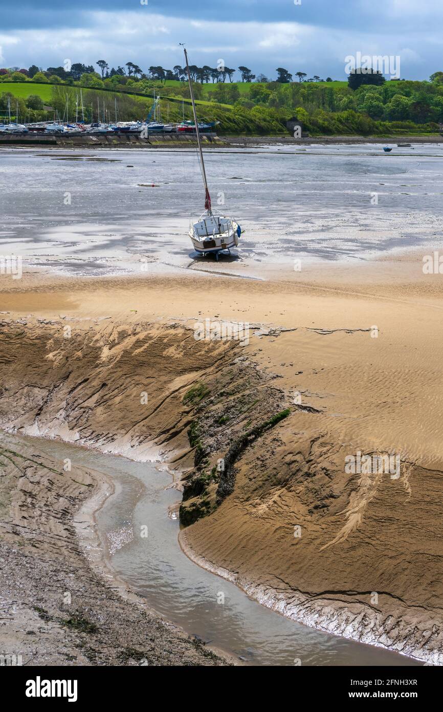A lone yacht sits on the mudflats at low tide in the small coastal ...