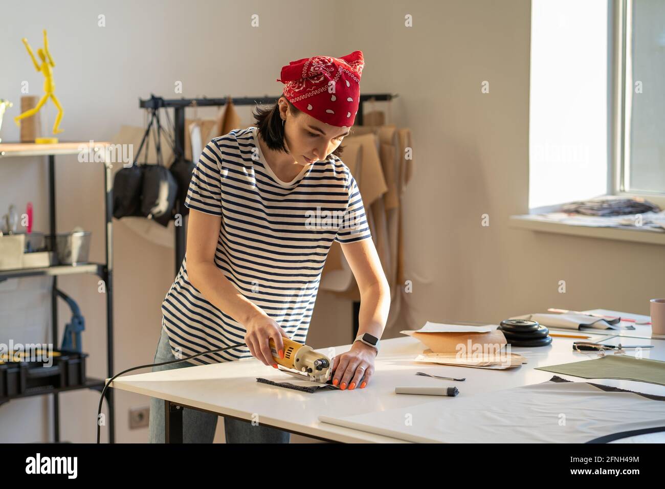 Busy tailor at work in studio. Female clothes designer cut fabric for ...