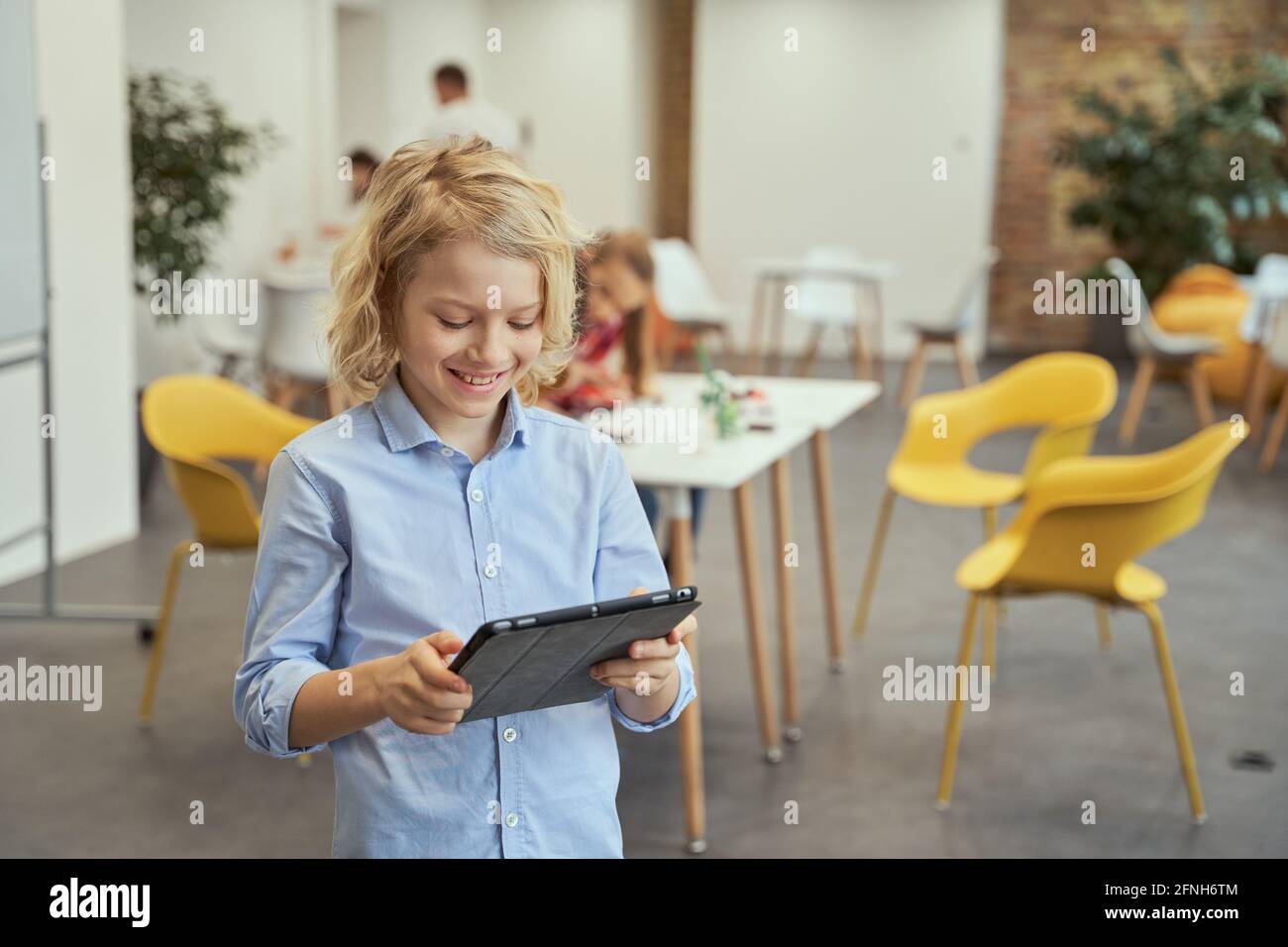 Portrait of clever little boy smiling, using tablet pc while posing for ...