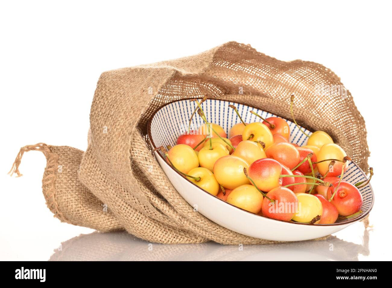 Sweet juicy yellow cherries in a ceramic plate and with a jute bag ...