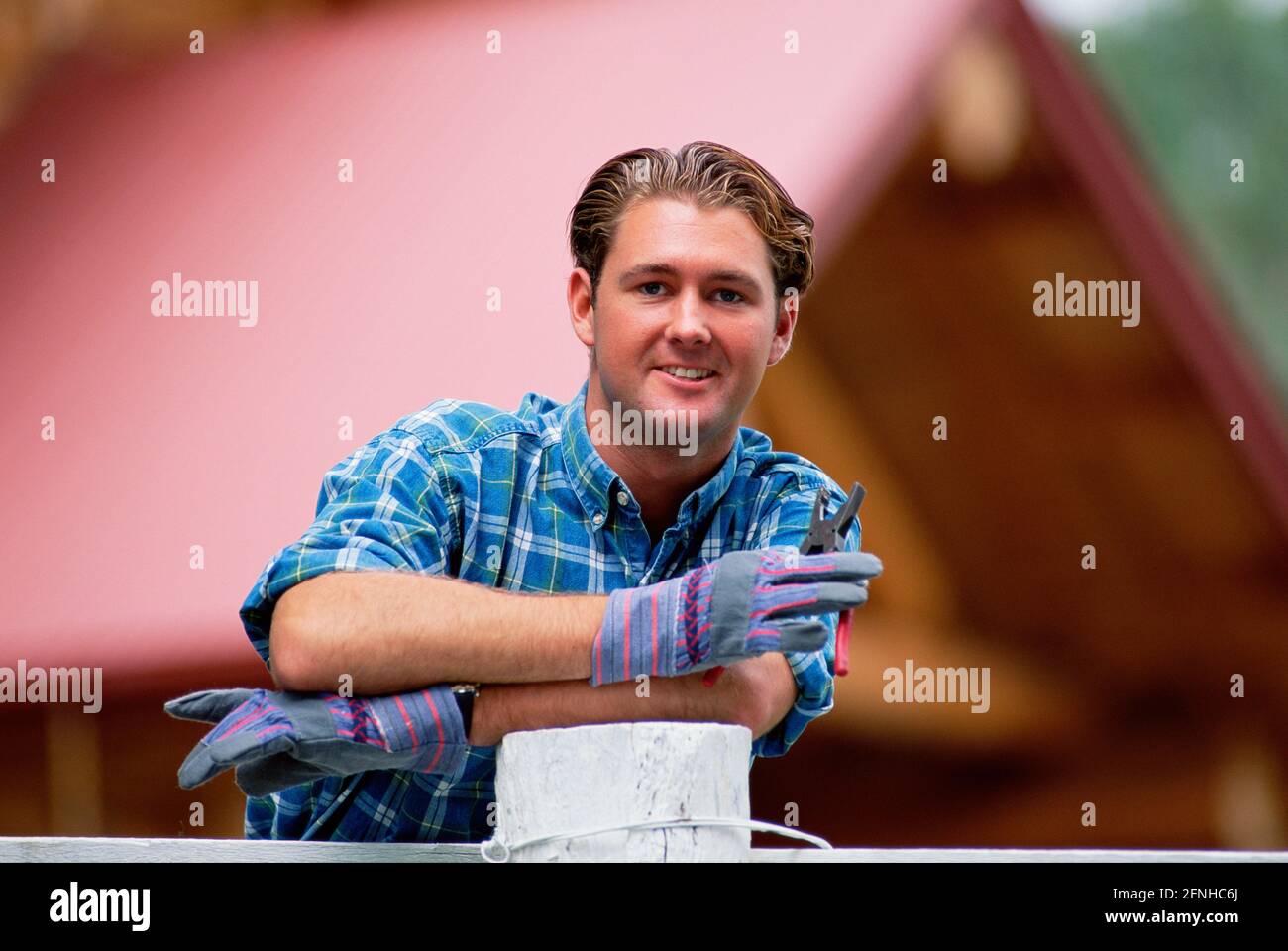 Lifestyle. Man standing doing maintenance outdoors by garden building ...