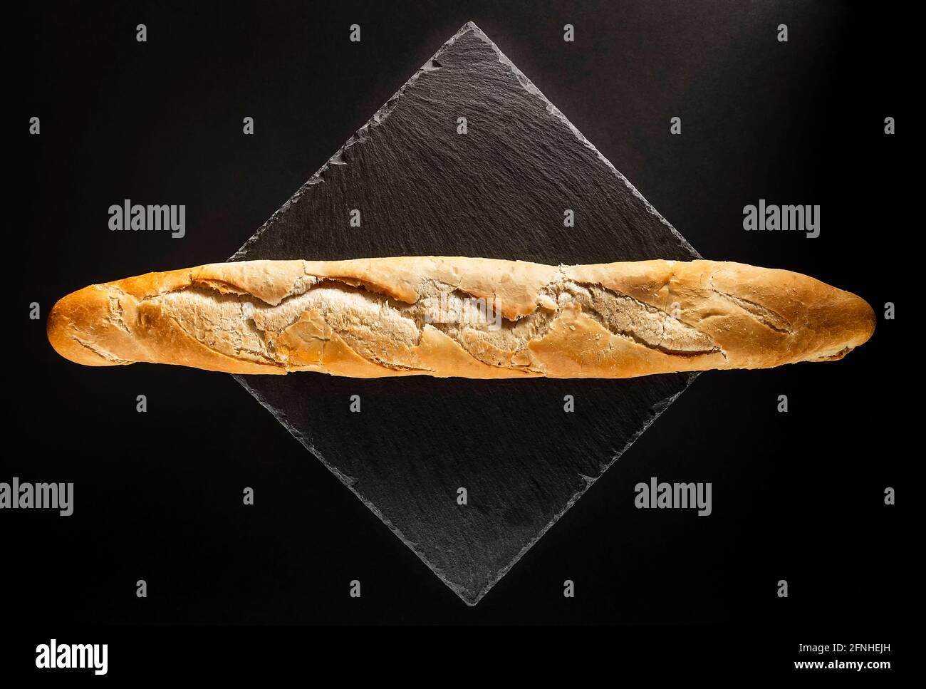 Loaf of artisan bread on a black slate.It is a still life with a black ...