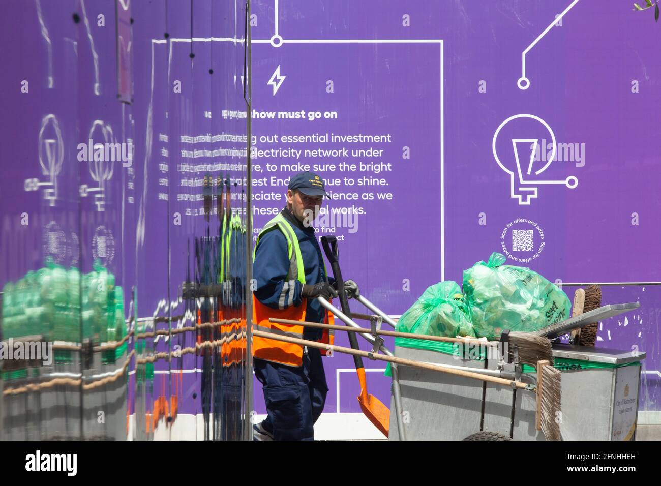 London, UK, 17 May 2021: A building site hoarding reflects passers-by ...