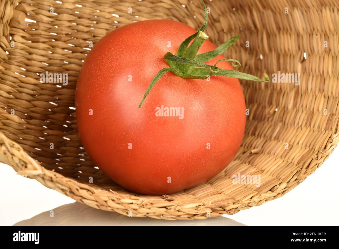 One bright pink tomato in a straw box Stock Photo - Alamy