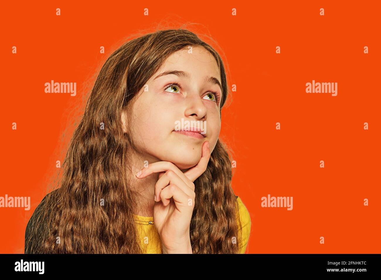 Teenage girl looks to the side with surprise on red background ...