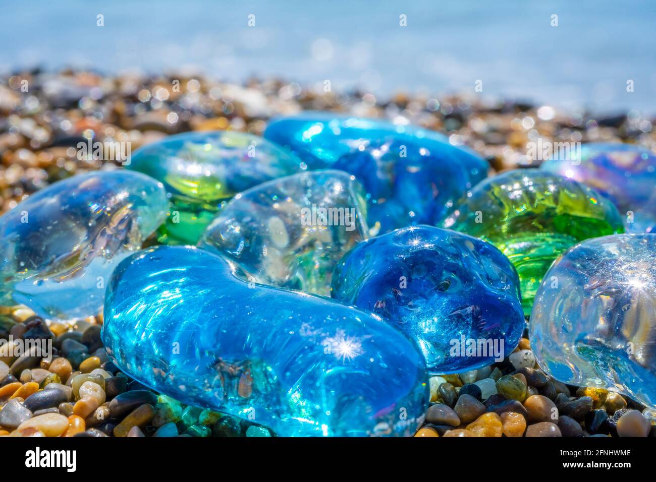 Beautiful shape glass and stones on the seashore. Azure clear sea water ...
