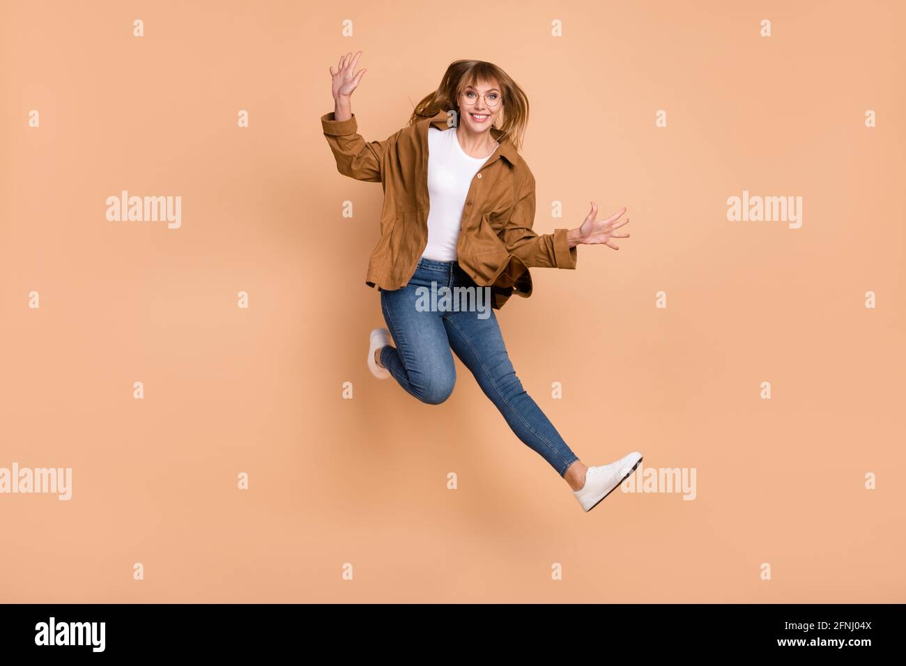 Full body photo of cheerful funky young woman jump up air raise hands ...