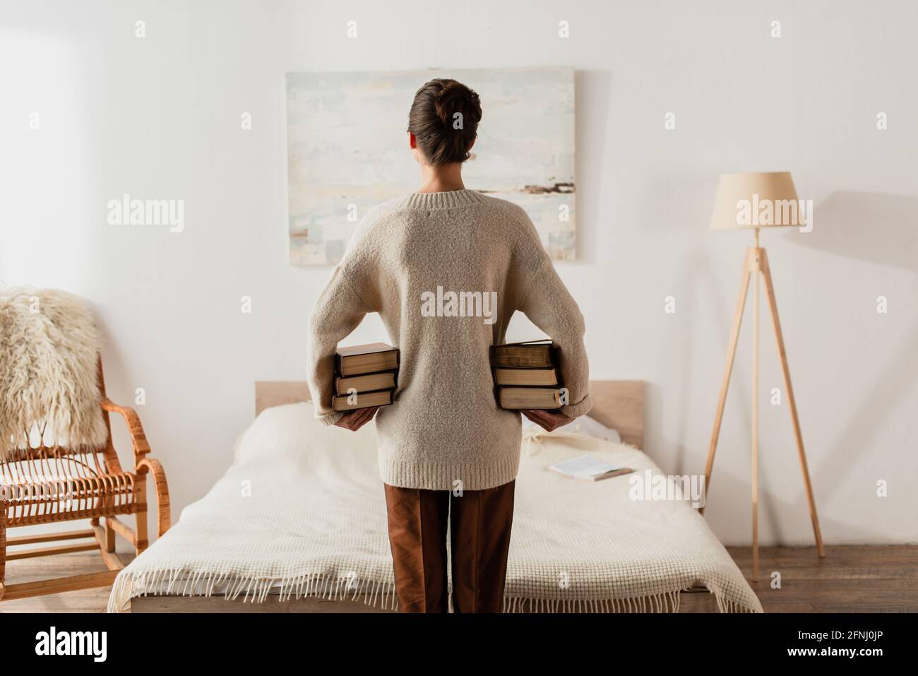 back view of woman holding stack of books in bedroom Stock Photo - Alamy