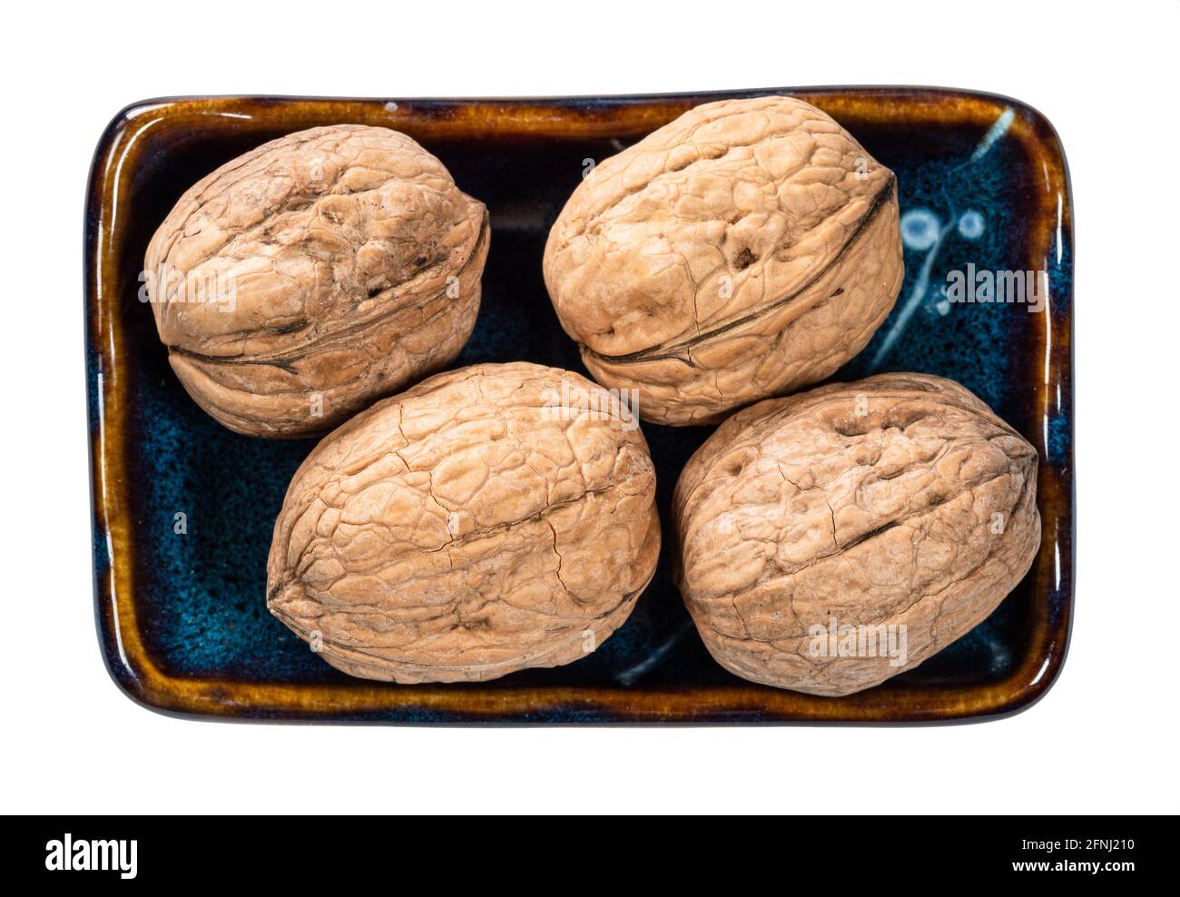 top view of several whole walnuts in bowl cutout on white background ...