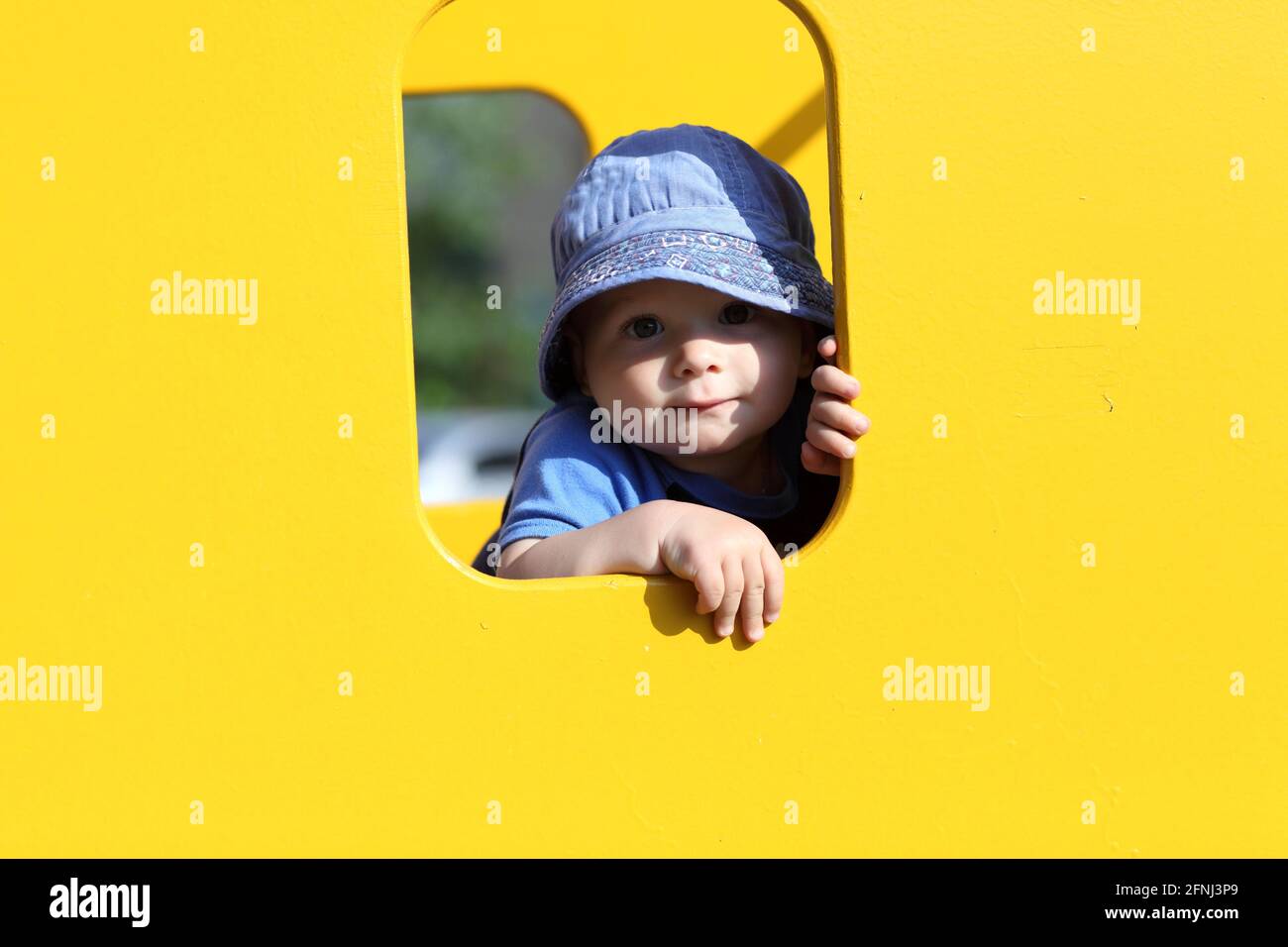 Little child is in yellow toy house at playground Stock Photo - Alamy