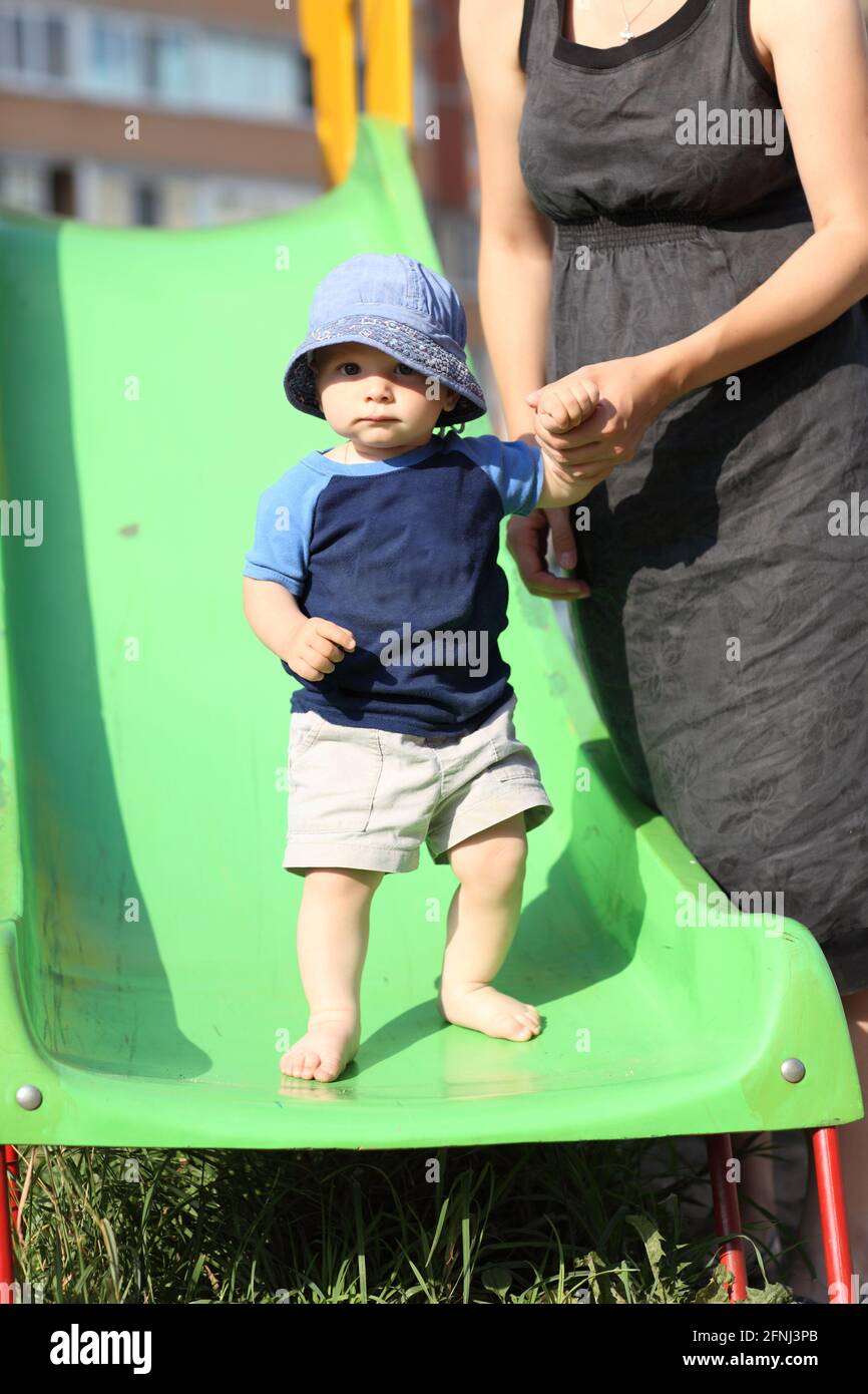 Child is standing on slide with mother's support Stock Photo - Alamy