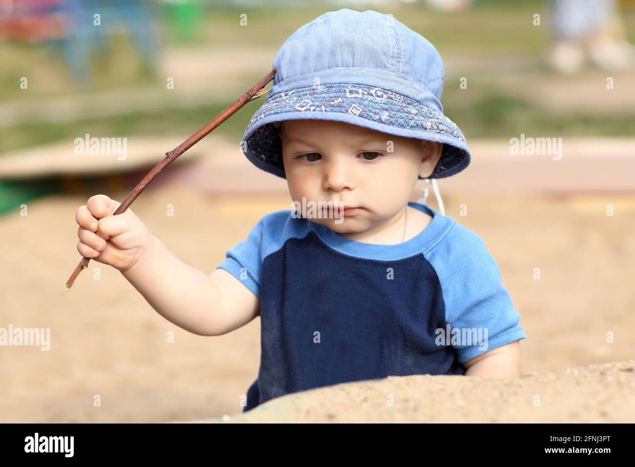 Child is holding stick in a sandbox Stock Photo - Alamy