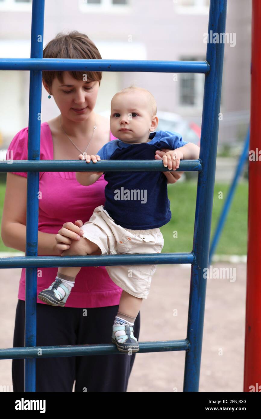 Baby is climbing step ladder with mother's assistance Stock Photo - Alamy