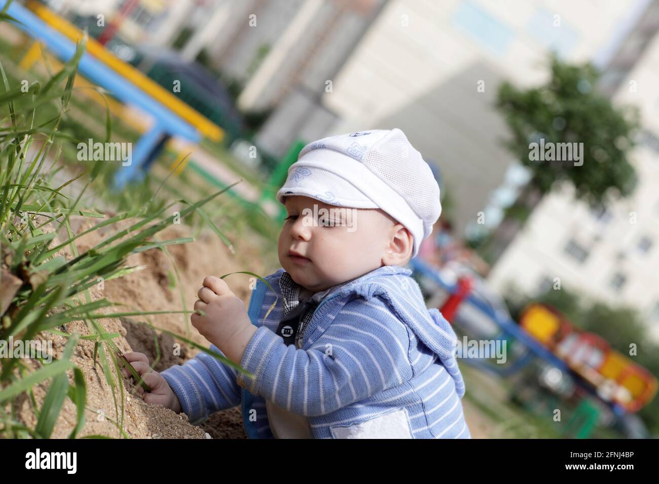 Little child is touching grass at playground Stock Photo - Alamy