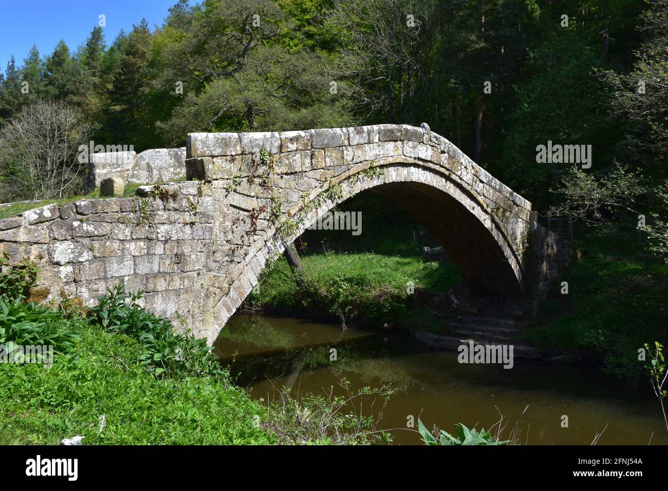 Stone arched beggar's bridge footpath over the water in Glaisdale ...