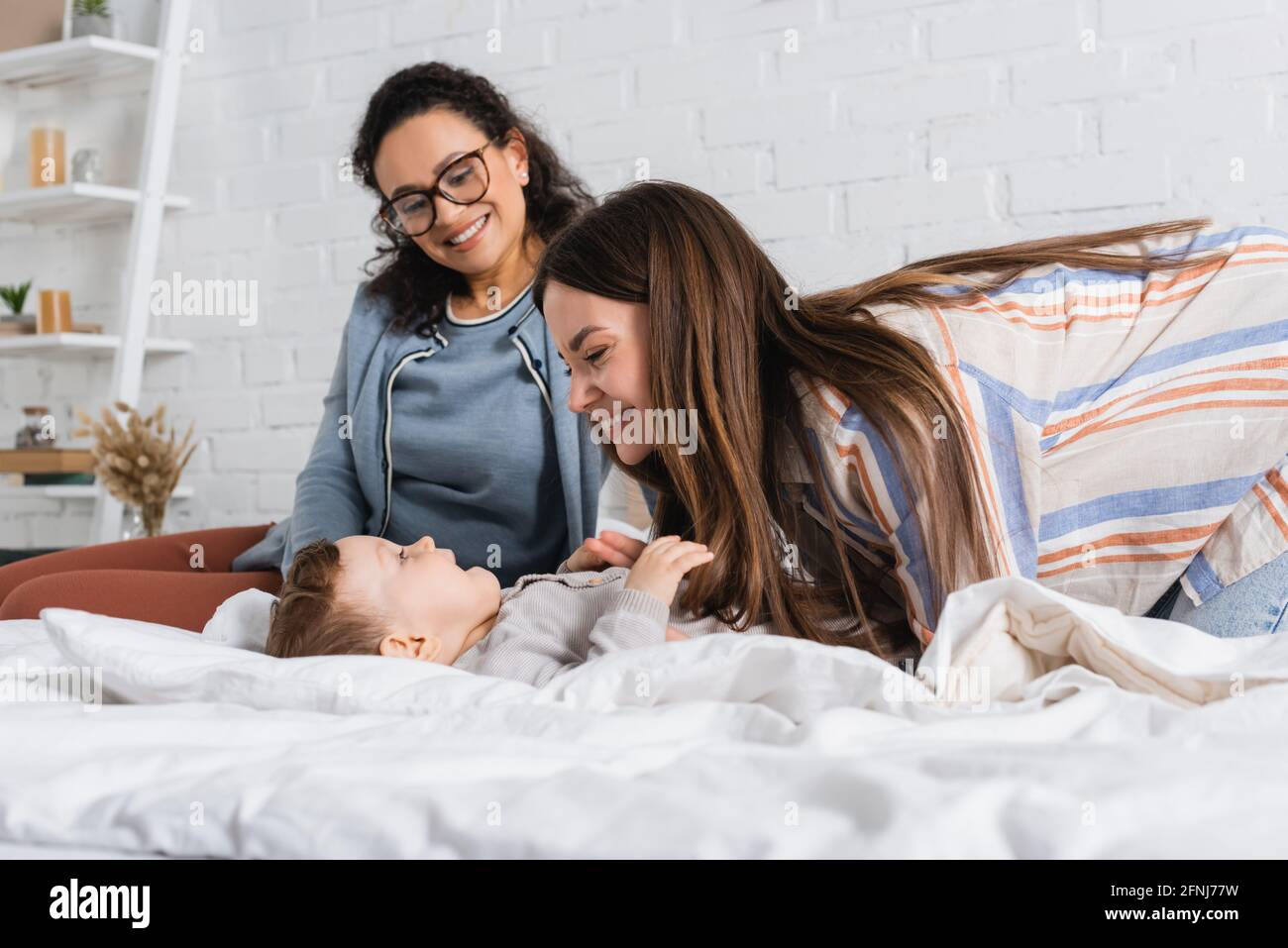 happy mother tickling baby boy near african american woman in glasses ...