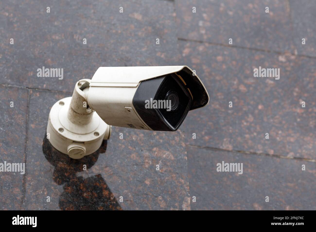 small white cheap surveillance camera on tan brown granite wall Stock ...