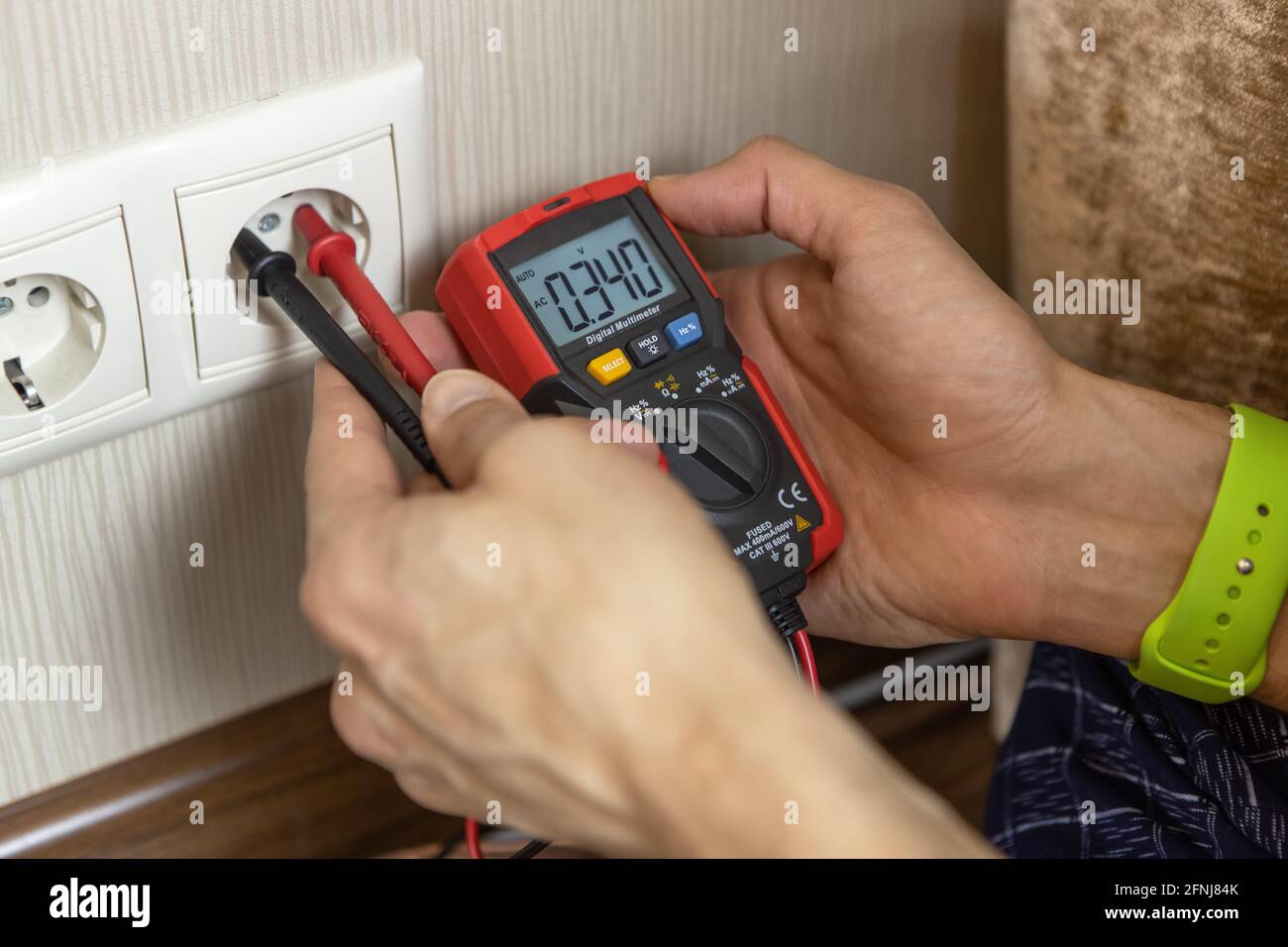An unrecognizable male technician measures the voltage at the outlet ...