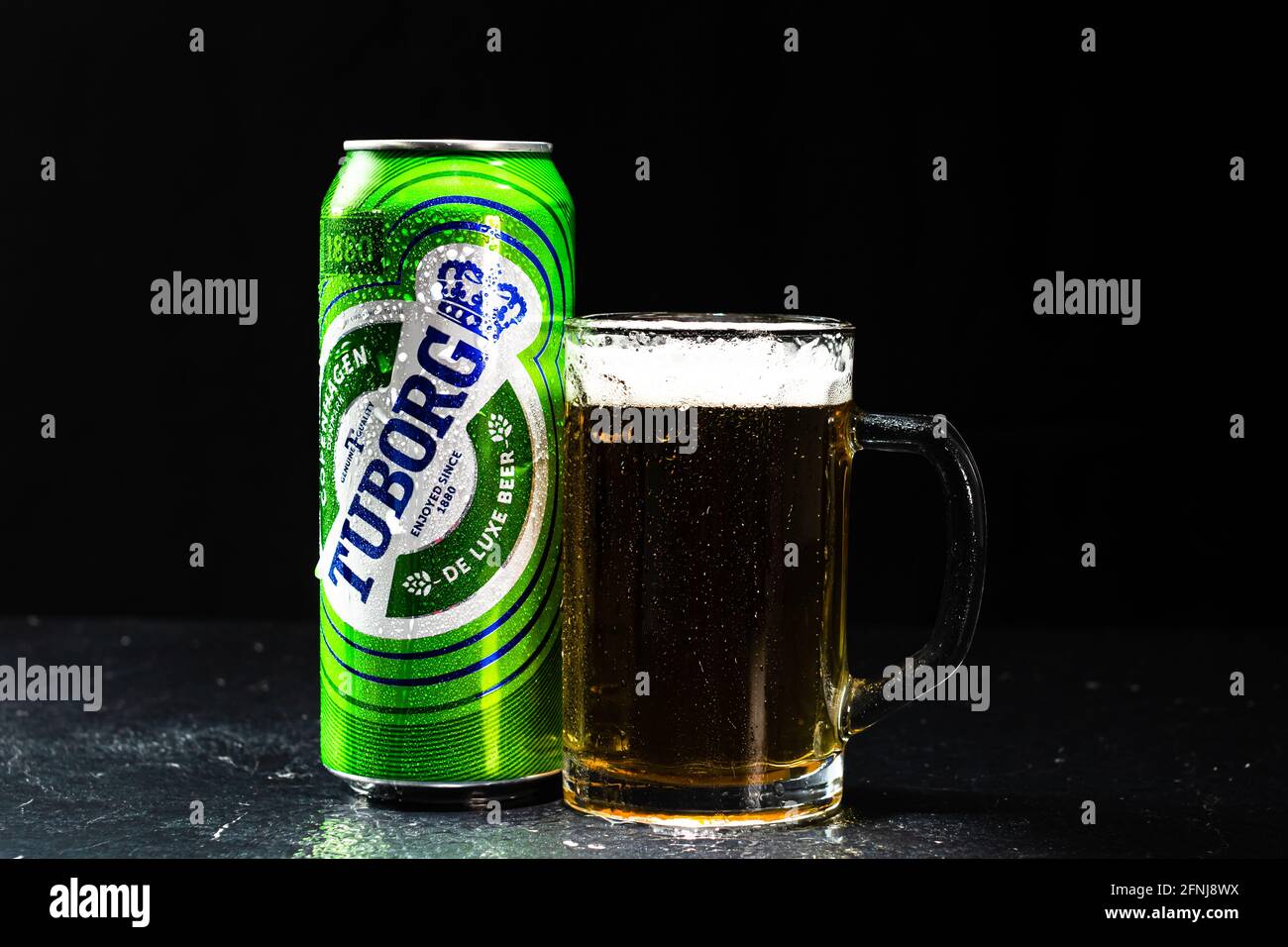 Can of Tuborg beer and beer glass on dark background. Illustrative ...