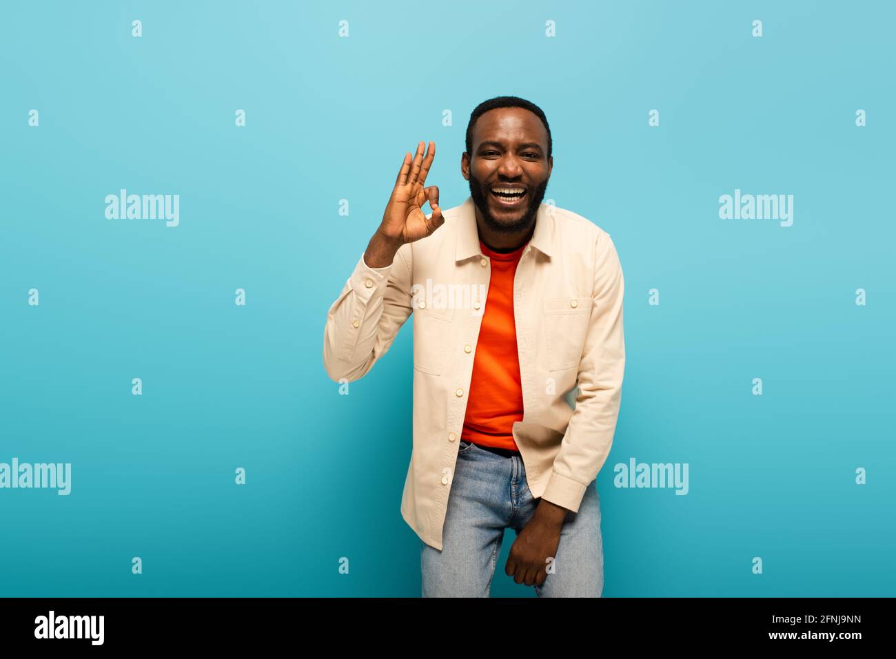 laughing african american man showing okay sign while looking at camera ...