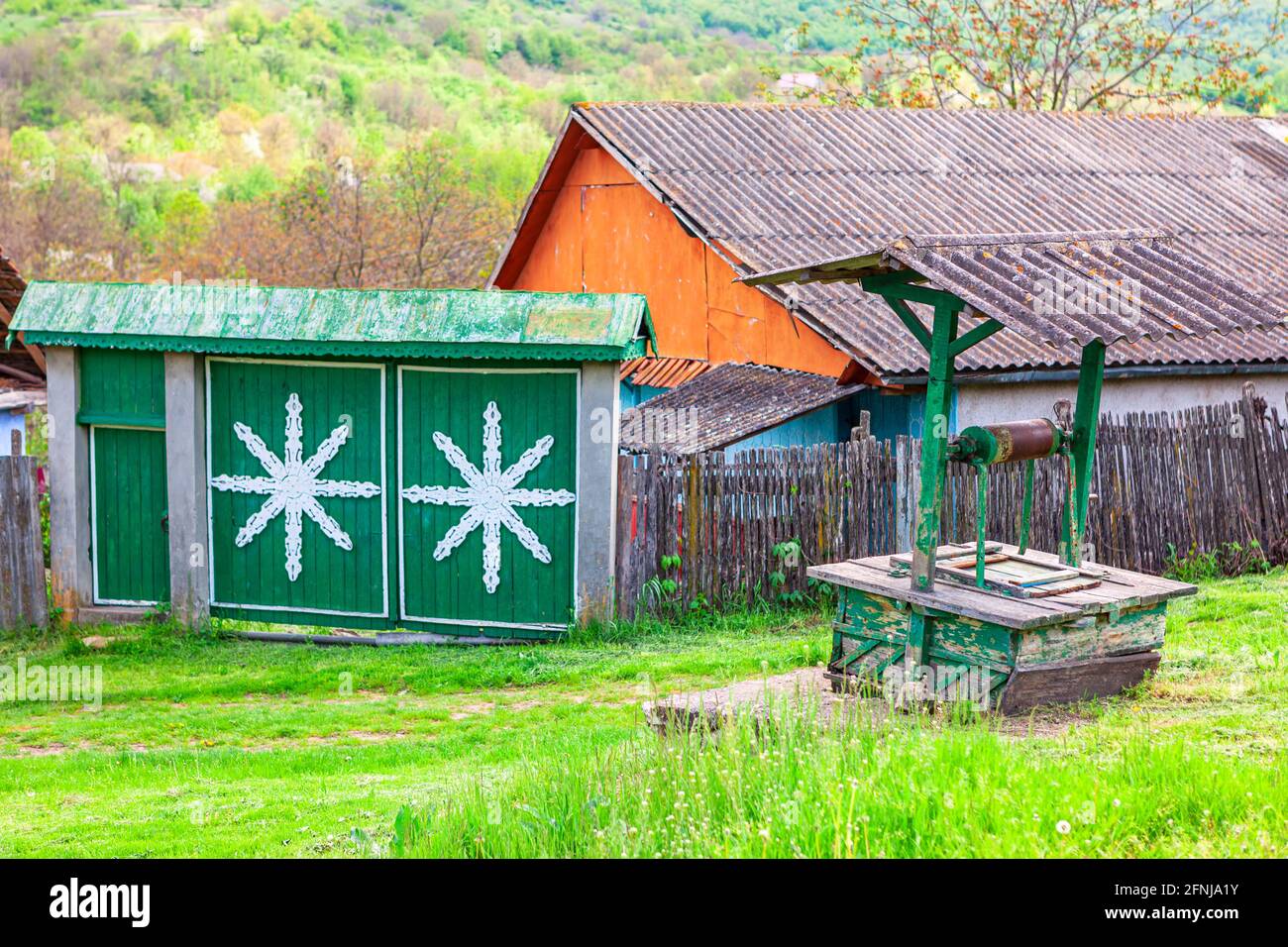Water well in front of country house . Traditional rustic house with ...