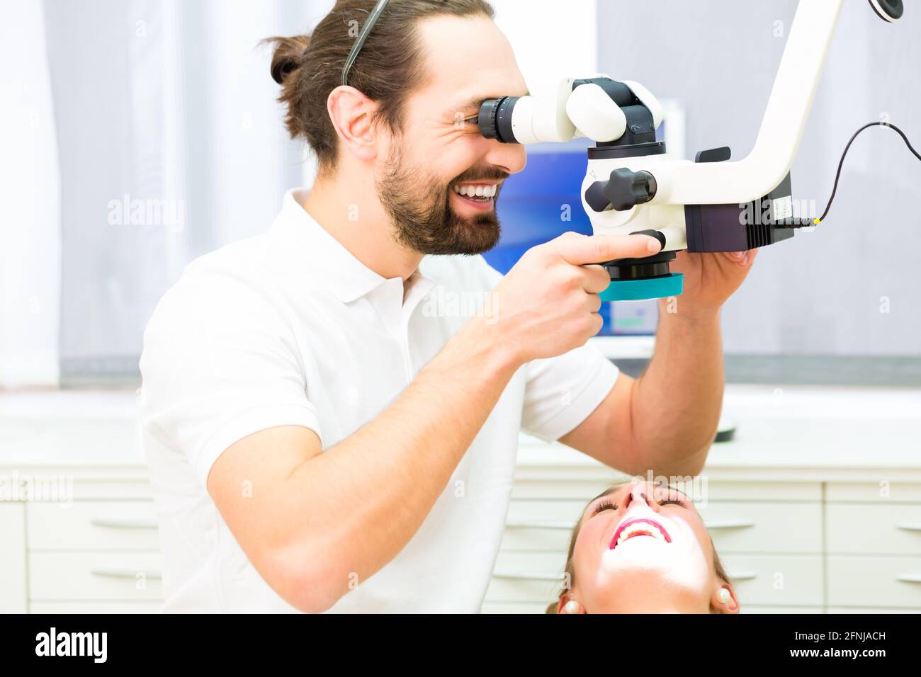 Dentist using microscope to check teeth of patient Stock Photo - Alamy