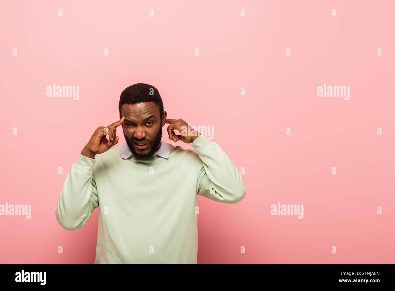 Confused african american man pointing at head on pink background Stock ...