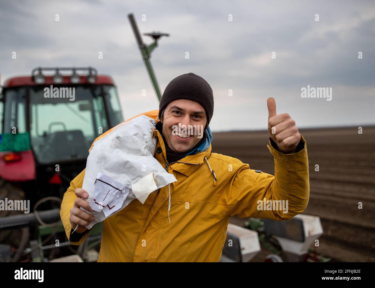 Portrait of handsome farmer carrying sack with seeds for sowing field ...
