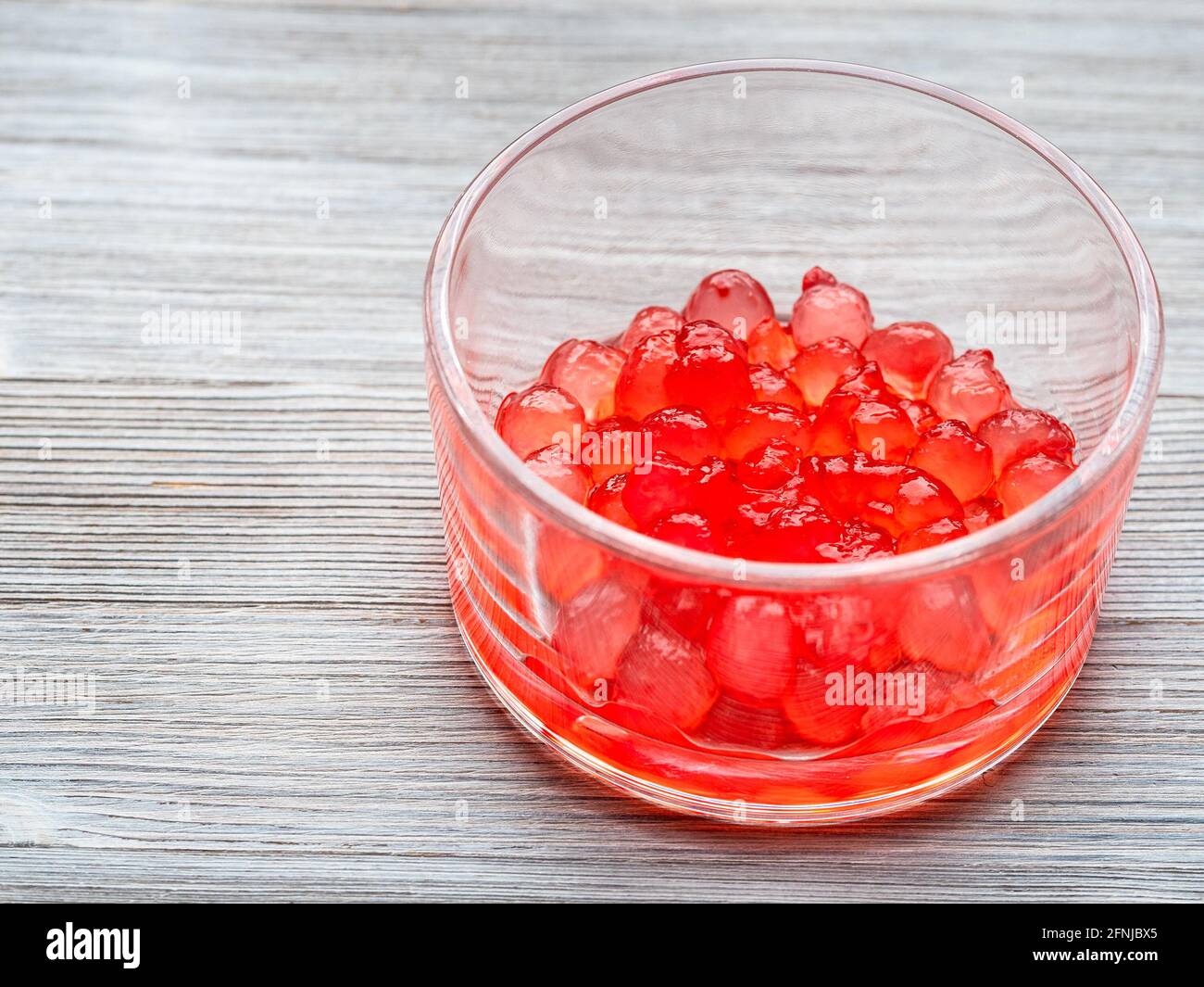 red colored boiled tapioca balls in glass bowl on gray wooden table ...