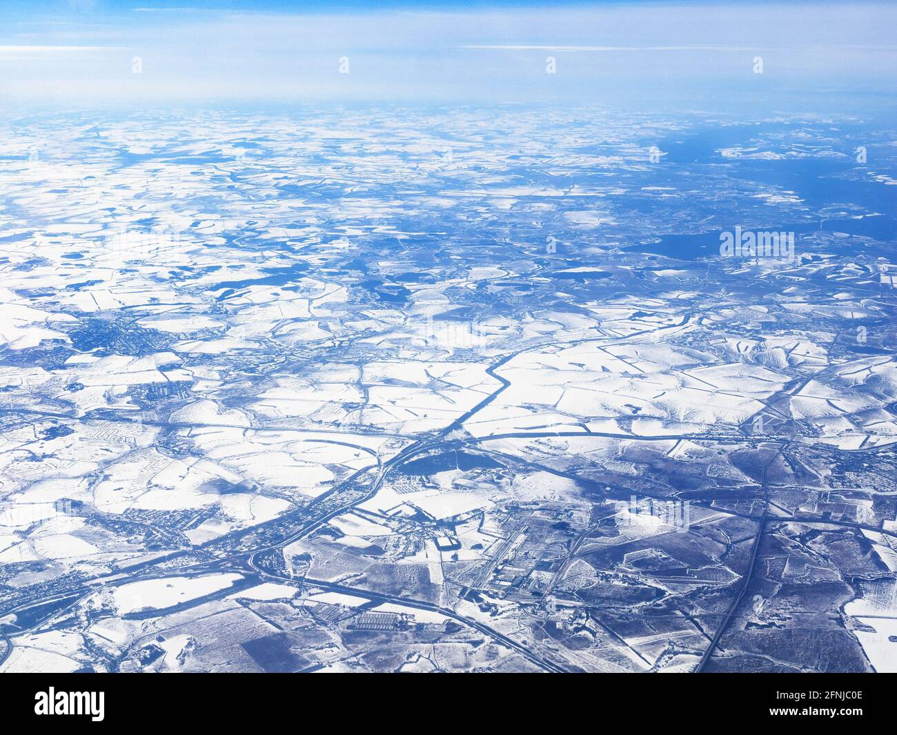aerial view of snow-covered earth from porthole while flying by plane ...