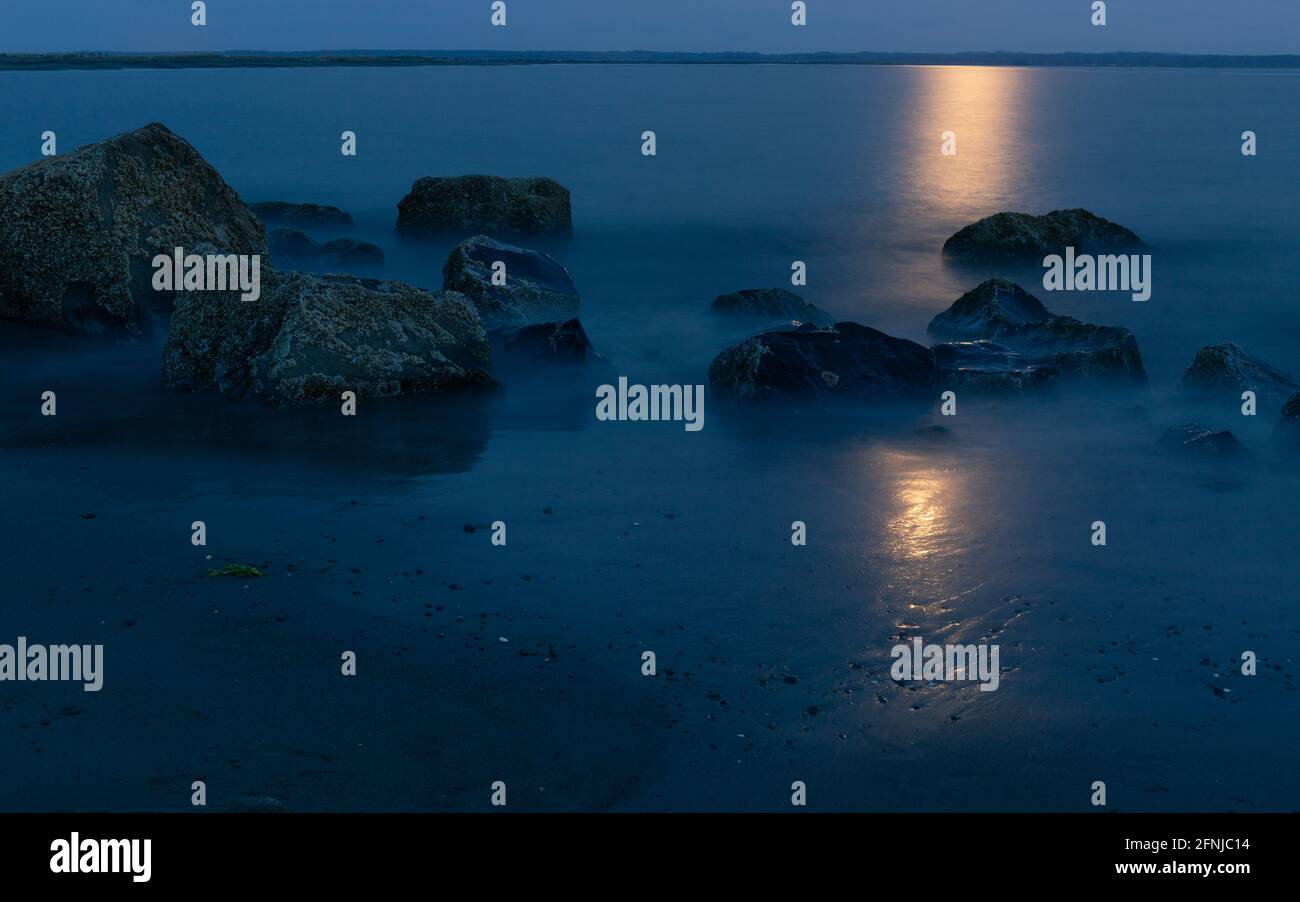Moon Reflecting on Ocean Beach During Blue Hour Stock Photo - Alamy