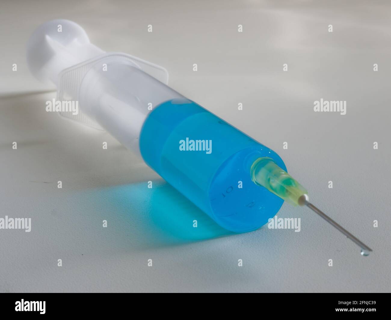 Plastic injection syringe with needle filled with a blue clear liquid ...