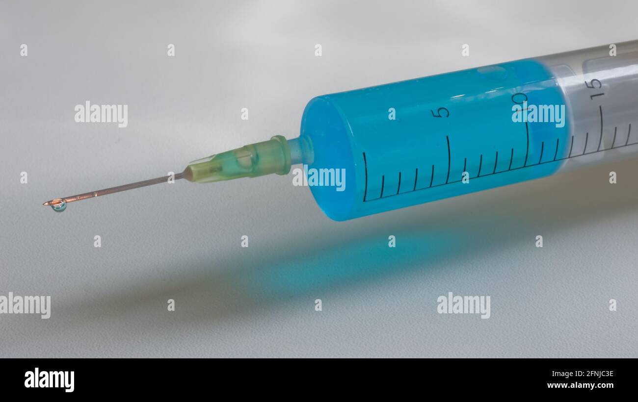 Plastic injection syringe with needle filled with a blue clear liquid ...
