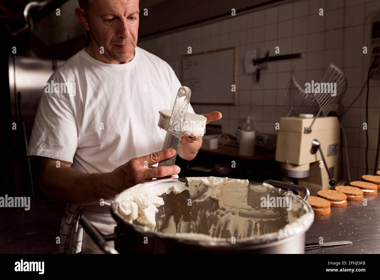 pastry chef in pastry shop filling stamps and cream. concept of ...