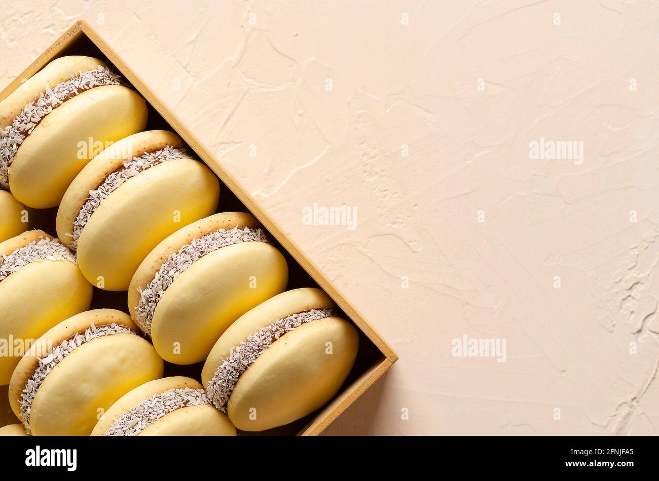 Cornstarch alfajores with milk caramel and coconut in a wooden box on a ...