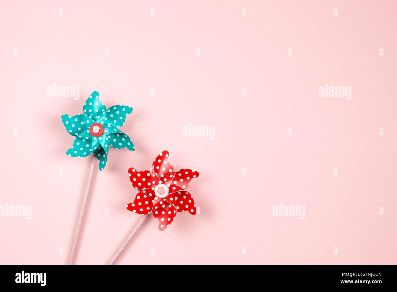 Two colorful windmill pinwheels on pastel pink background. Top view ...